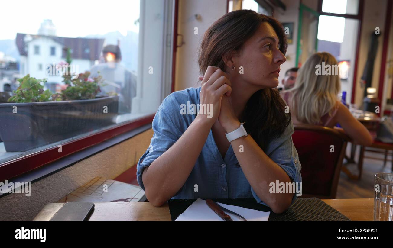 Female customer seated at restaurant staring out window. One ...