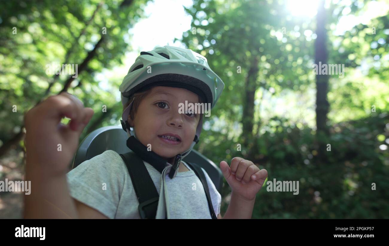 Happy child wearing bicycle helmet outdoors in forest park. Little boy ...