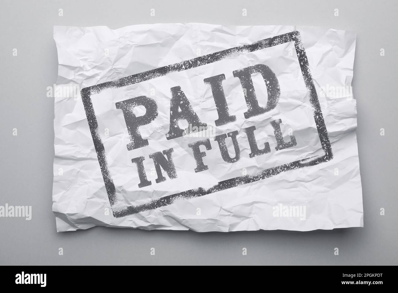 Crumpled paper with stamp PAID IN FULL on grey background, top view ...
