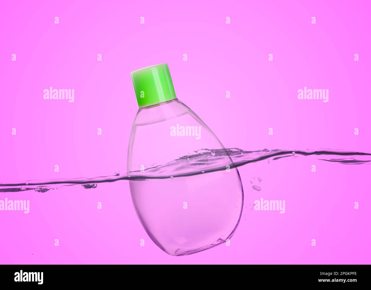 Bottle of baby oil floating in water against pink background Stock ...