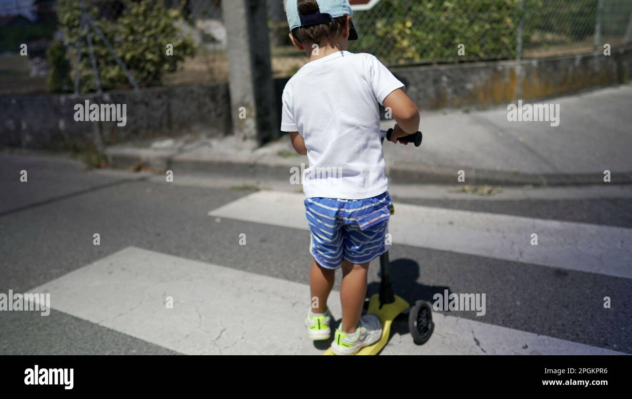 Child crossing crosswalk with toy scooter. Active little boy riding ...