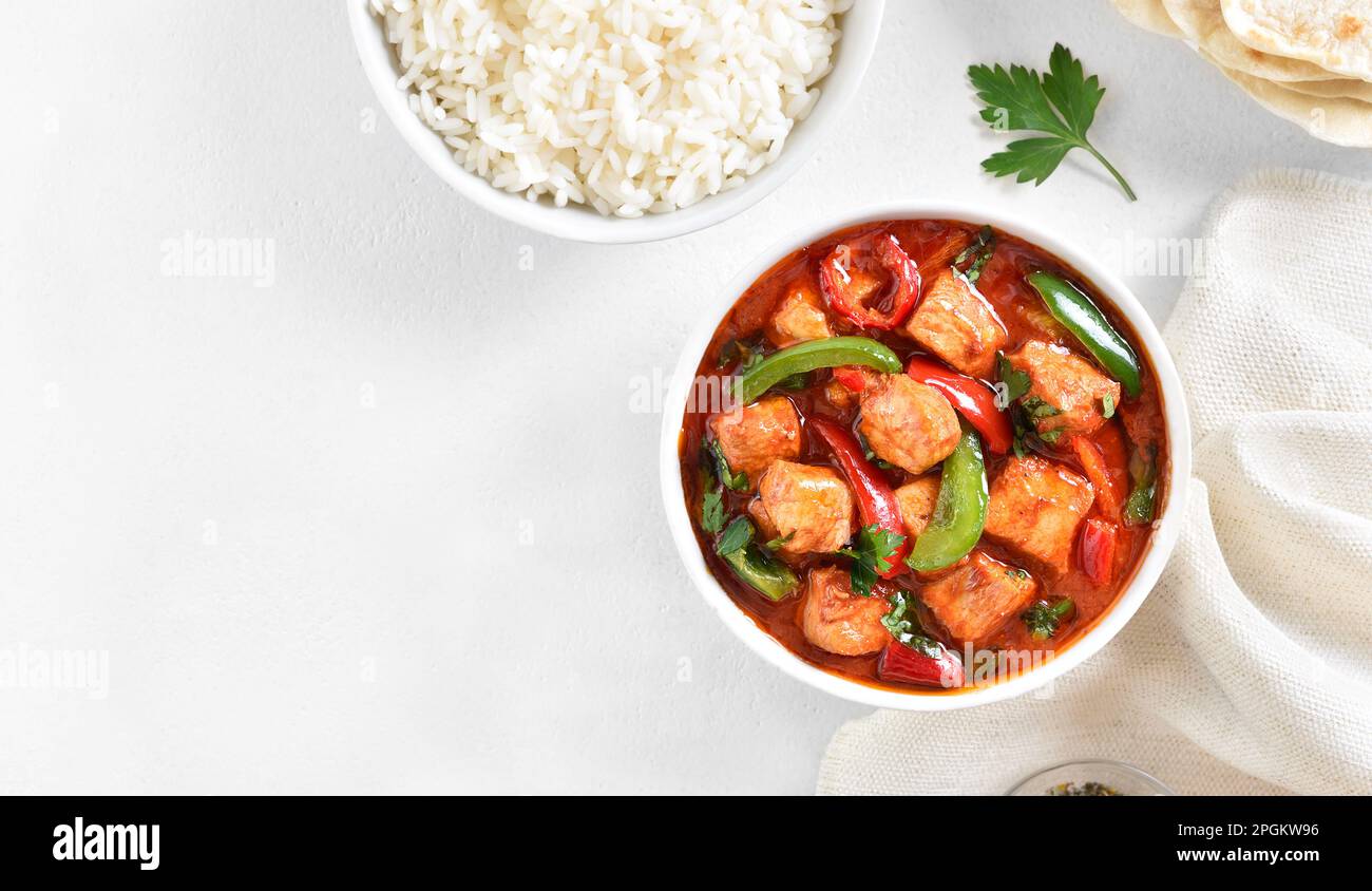 Thai style red chicken curry with vegetables in bowl over light ...