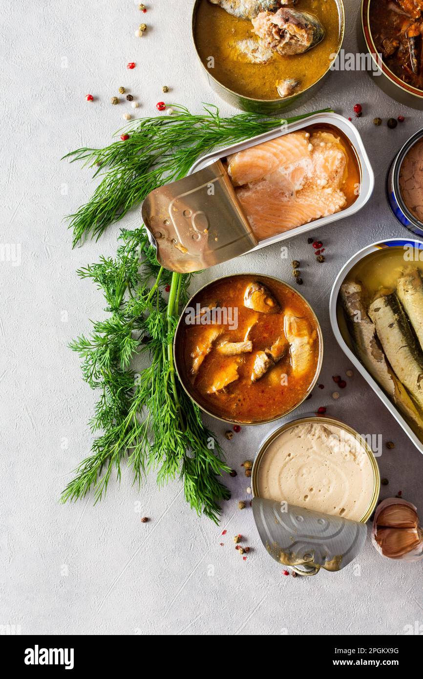 Different open tin cans with canned fish among spices and herbs, canned ...