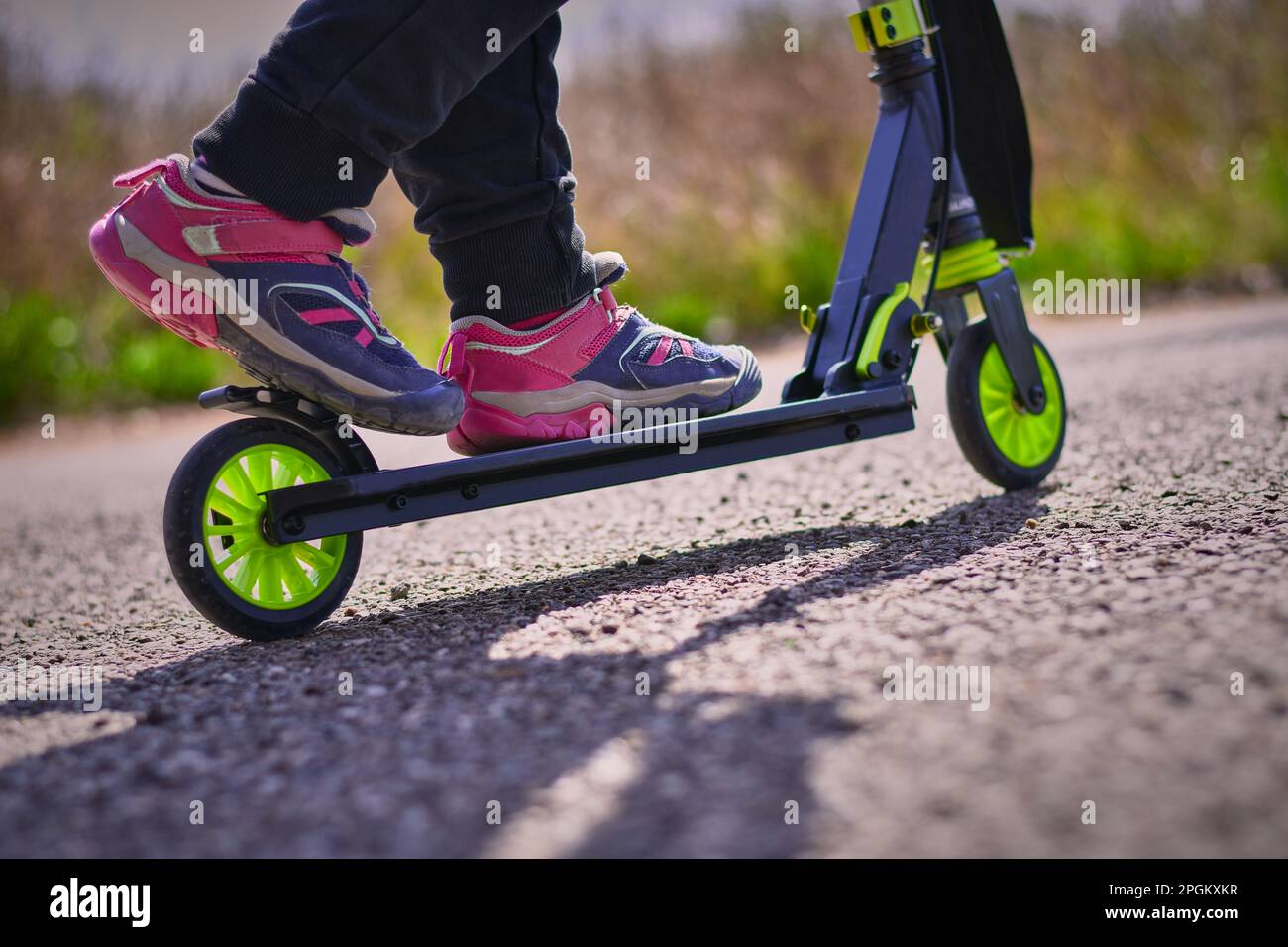 A girl rides and brakes with her foot the rear wheel of a scooter on a ...