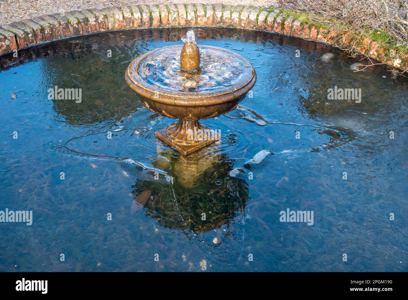 water fountain flowing onto iced pool of water on a cold winter day ...