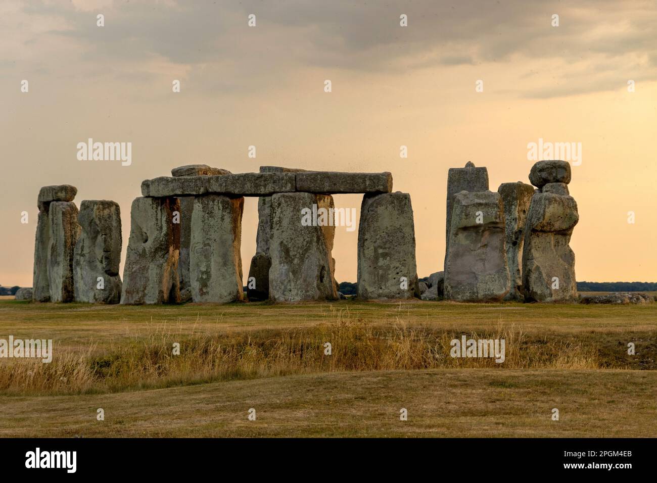 The Stonehenge monoliths stand in a lush green field, with a dramatic ...
