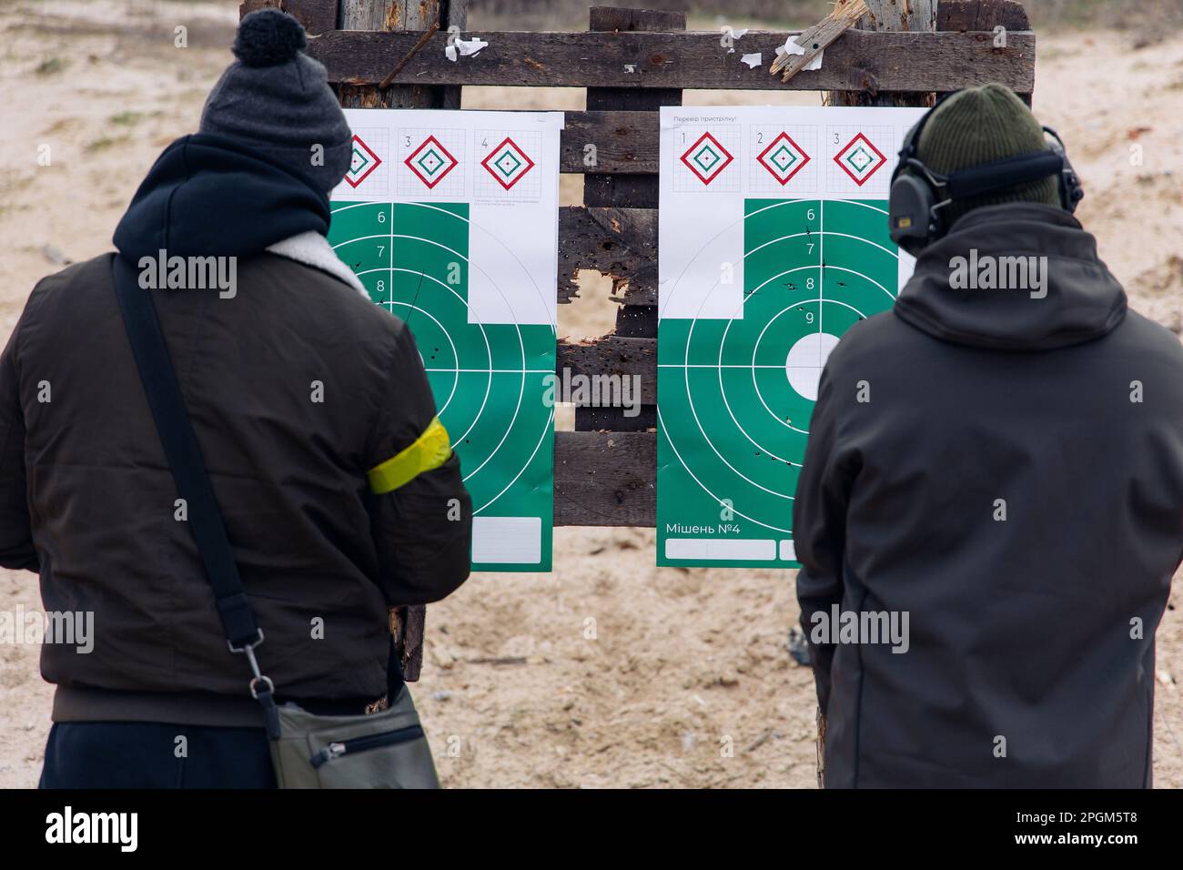 Two shooters examine their targets with shot through holes at a ...