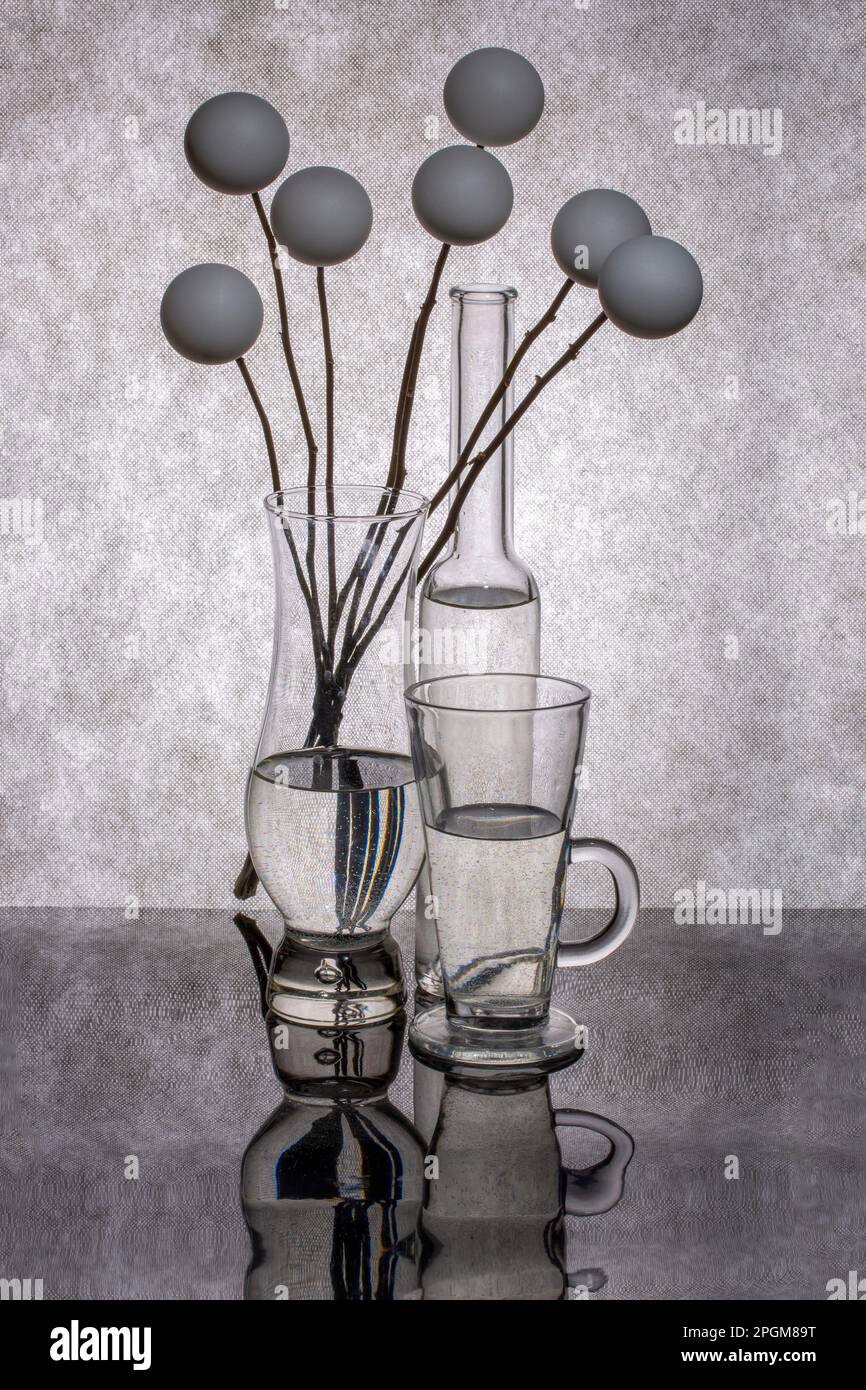 Still life with glassware on a reflective surface and a bouquet of ...