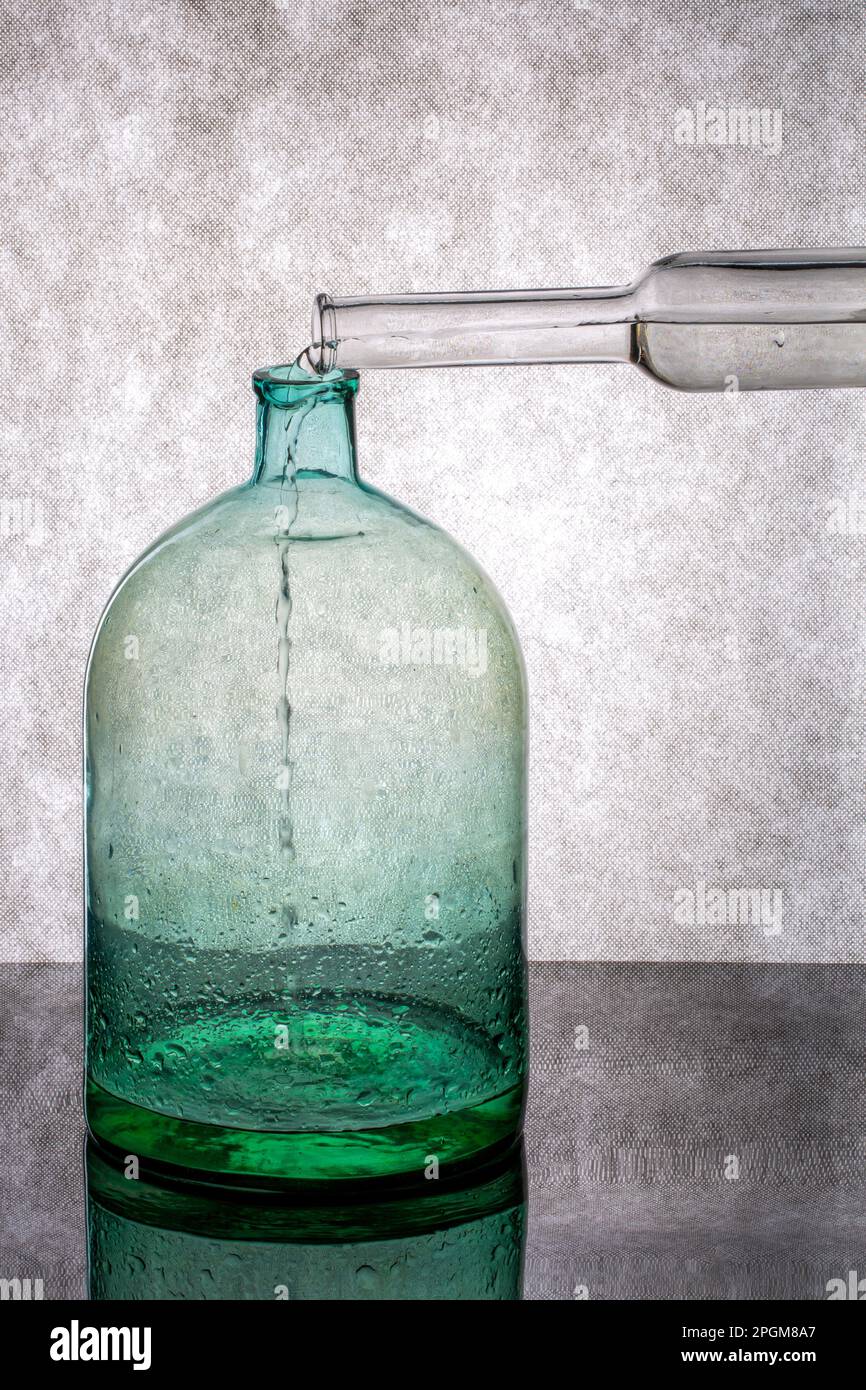 Pouring water from a bottle into a glass jar Stock Photo - Alamy