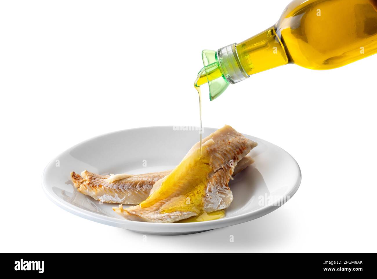 Cod fillet in white dish with extra virgin olive oil poured from bottle ...