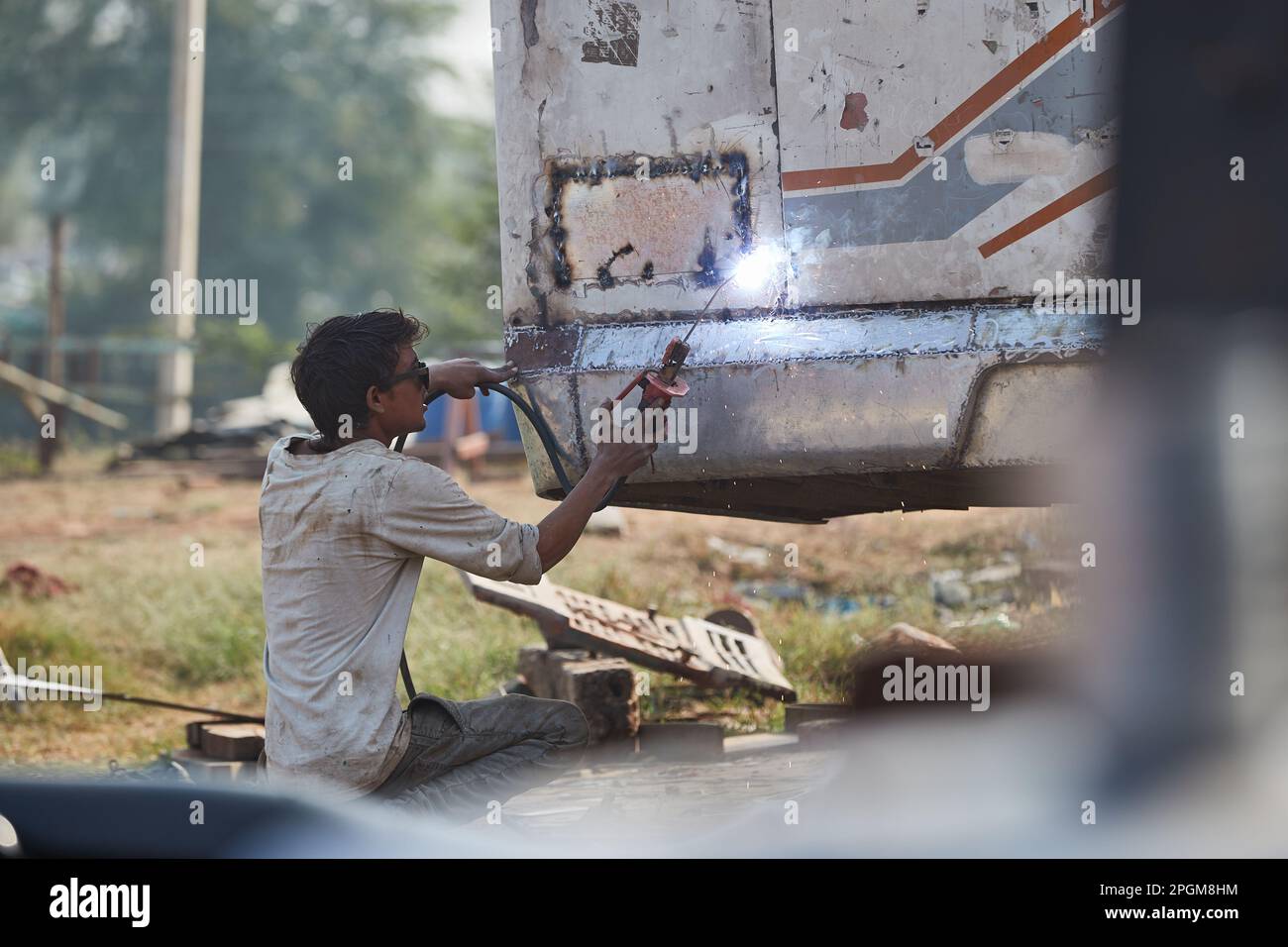 Delhi, India - teenage boy welding on the backside of a bus Stock Photo ...