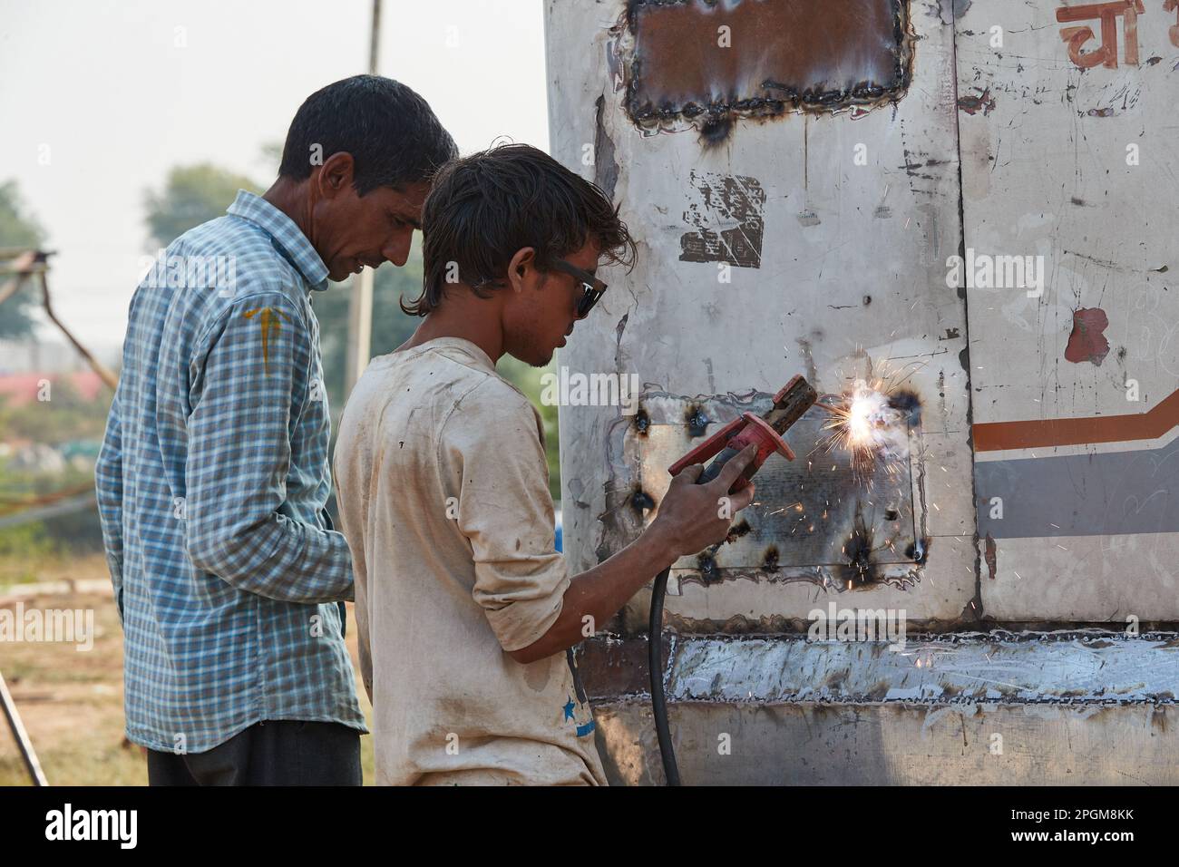 Delhi, India - teenage boy welding on the backside of a bus Stock Photo ...