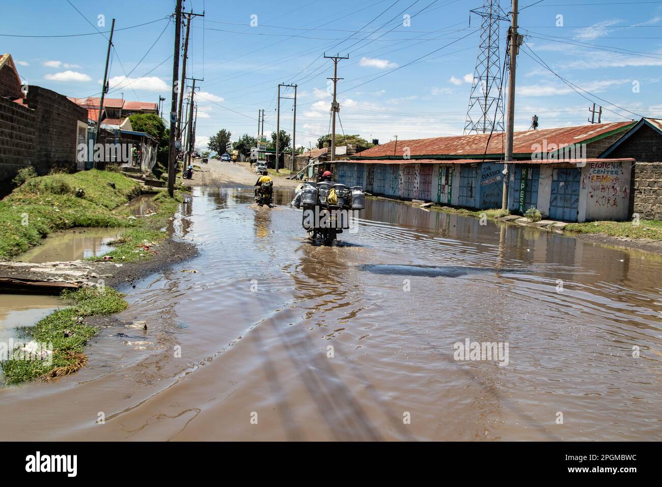 Motorcyclists navigate through a flooded road in Nakuru, following ...