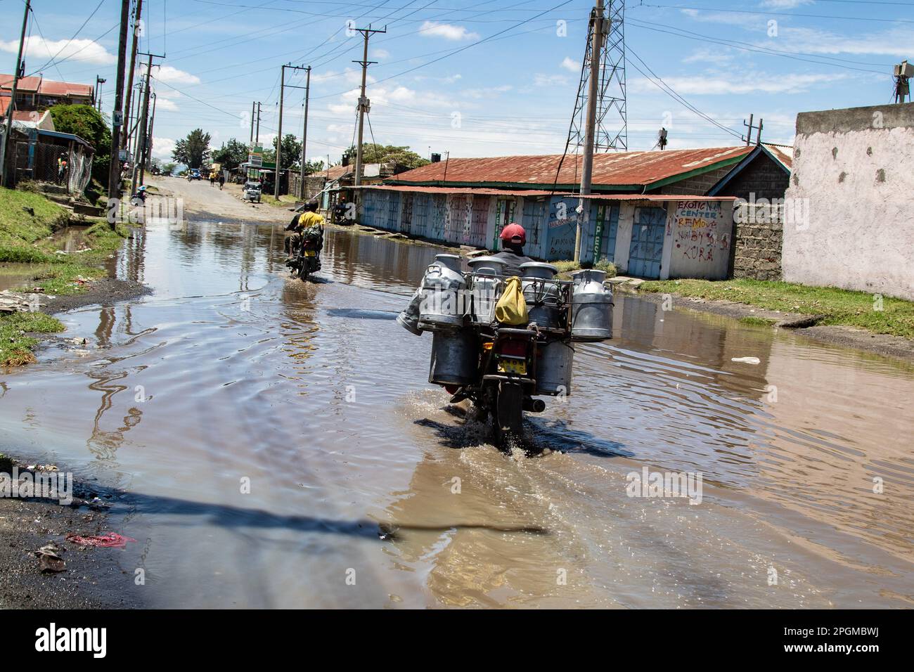 Motorcyclists navigate through a flooded road in Nakuru, following ...