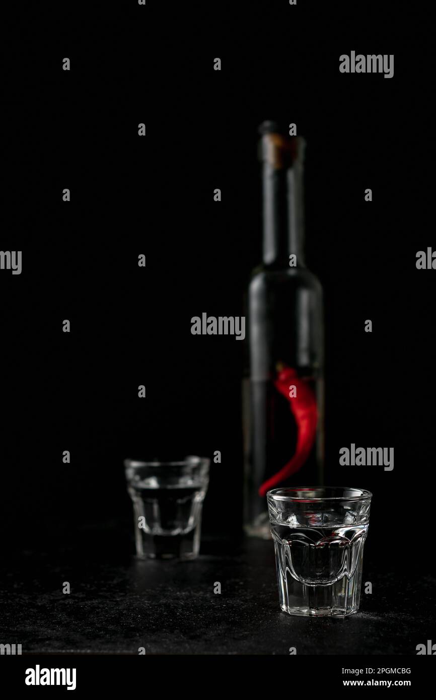 Hot pepper vodka on a black background, space for text Stock Photo - Alamy