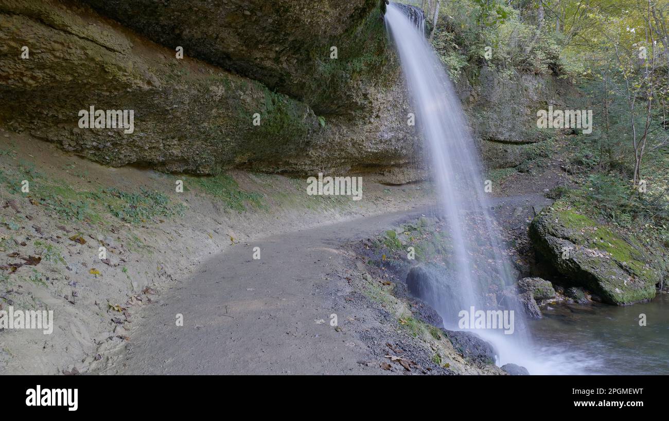 Path next to rock under a small waterfall at Scheidegger Waterfalls ...