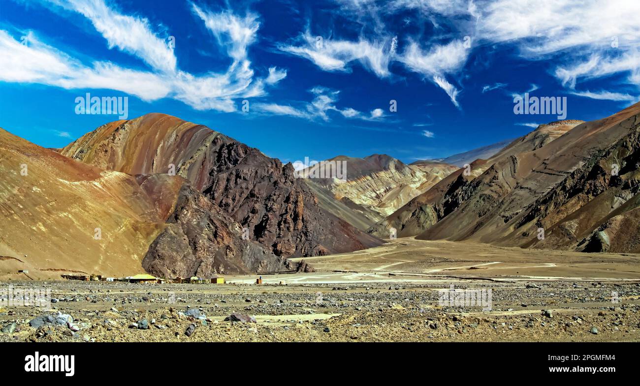 Dry unvegetated stony barren valley wide, gray rugged mountains, small ...