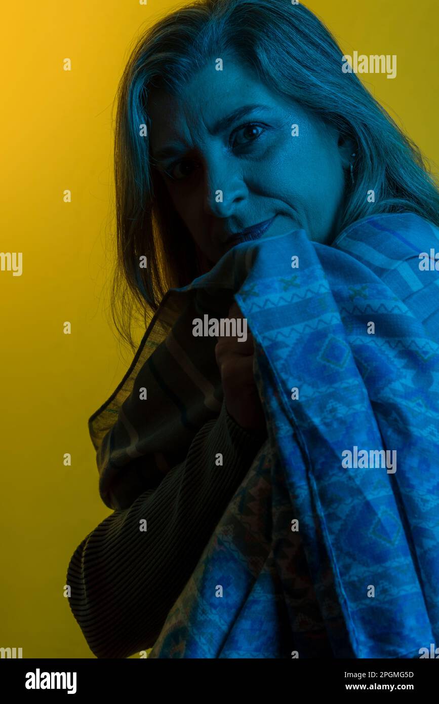 Beautiful woman portrait under blue light. Isolated on dark yellow ...