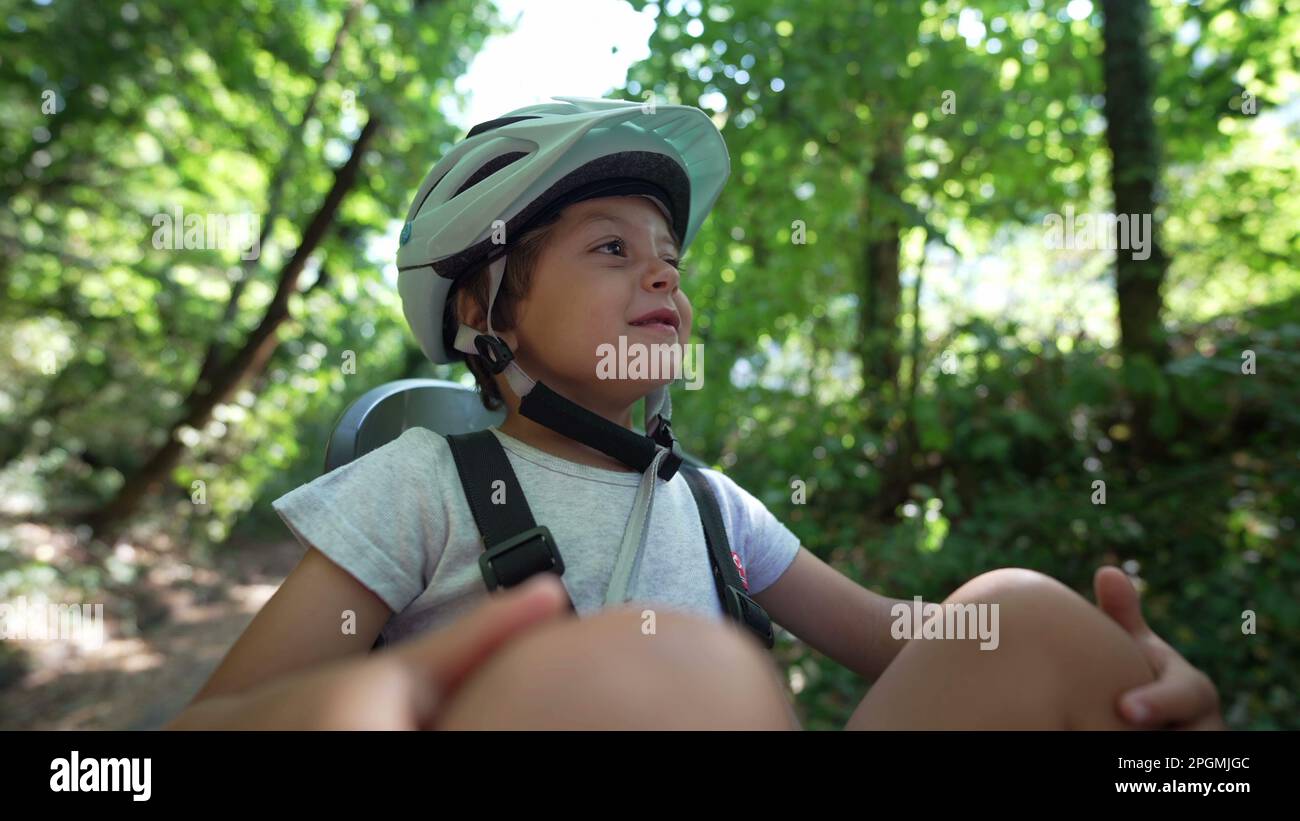One happy child waving hello seated in bike seat wearing helmet ...