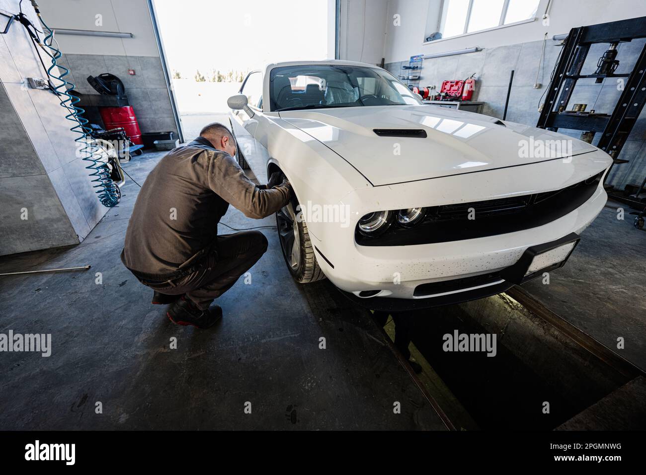 Mechanic in service repair station working with muscle car. Man worker ...