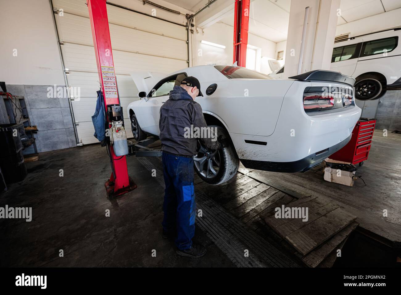 Mechanic in service repair station working with muscle car in lift ...