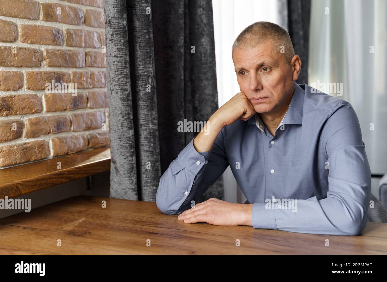Portrait of a pensive middle-aged man sitting at a table. The man ...