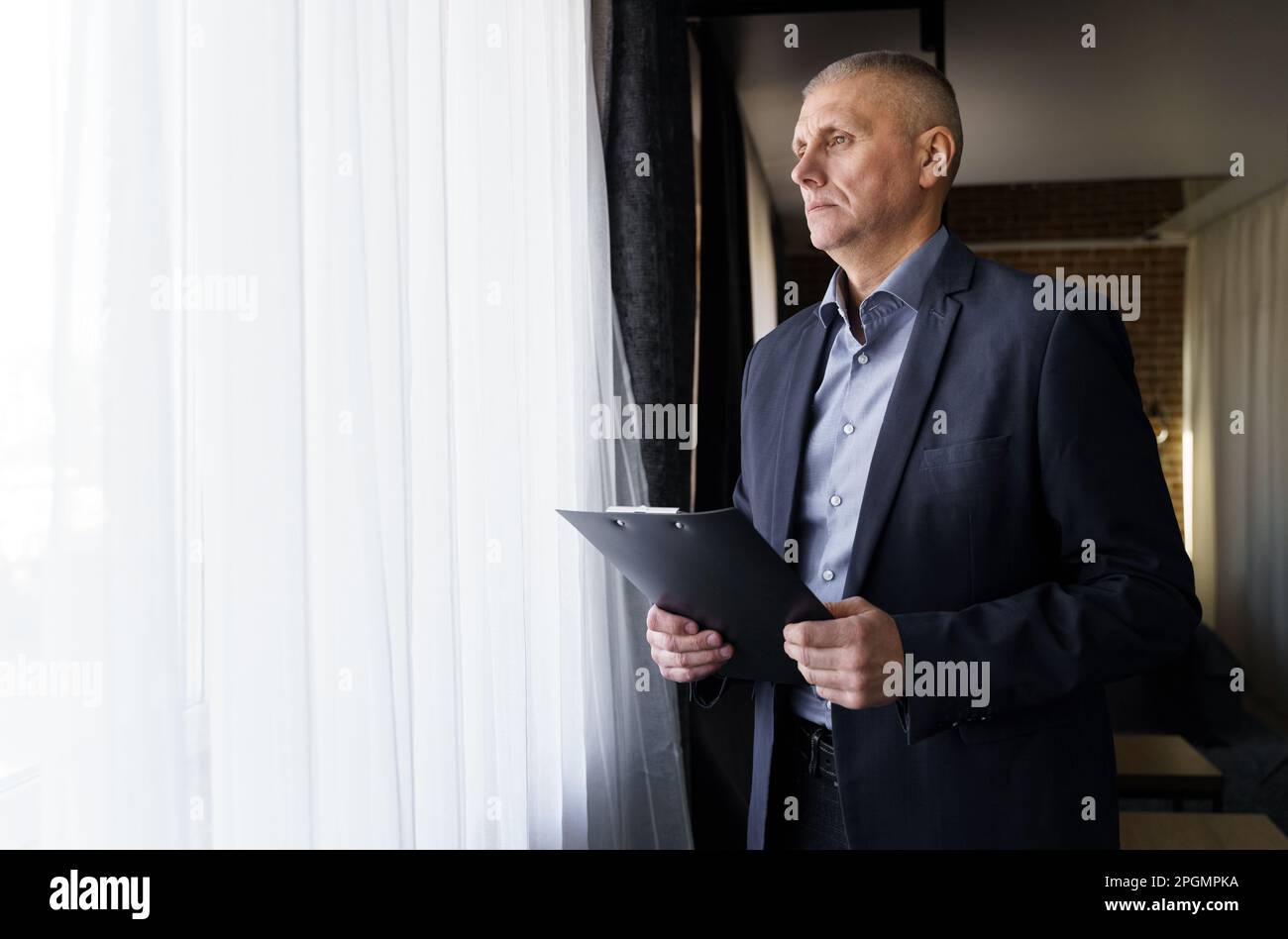 Portrait of a businessman who stands and holds documents in his hands ...