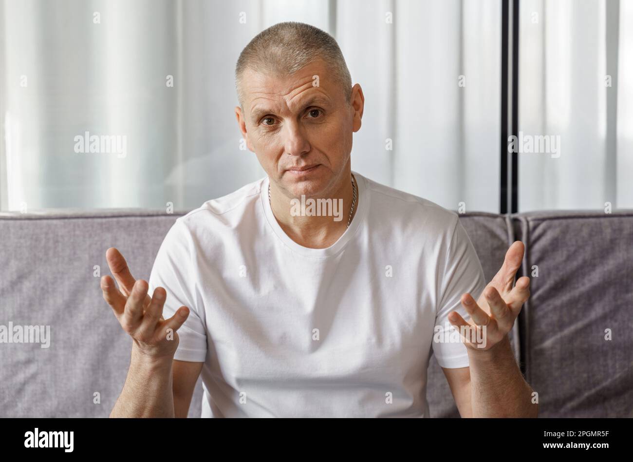 A happy middle-aged European man gestures with his hands in front of ...