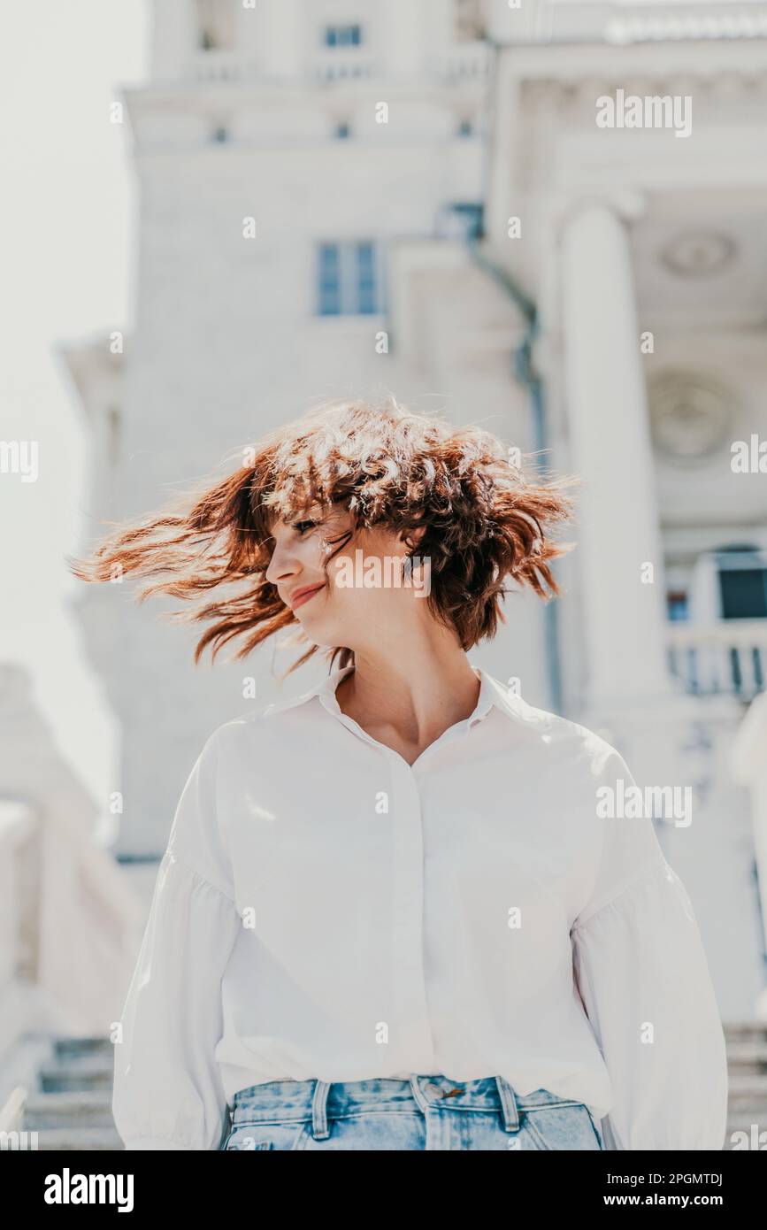 Wind hair style. A portrait of a woman outdoors, her shoulder-length ...