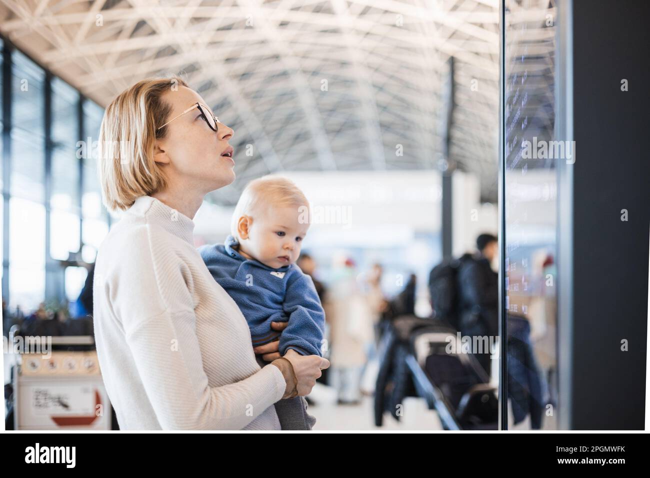 Mother traveling with child, holding his infant baby boy at airport ...
