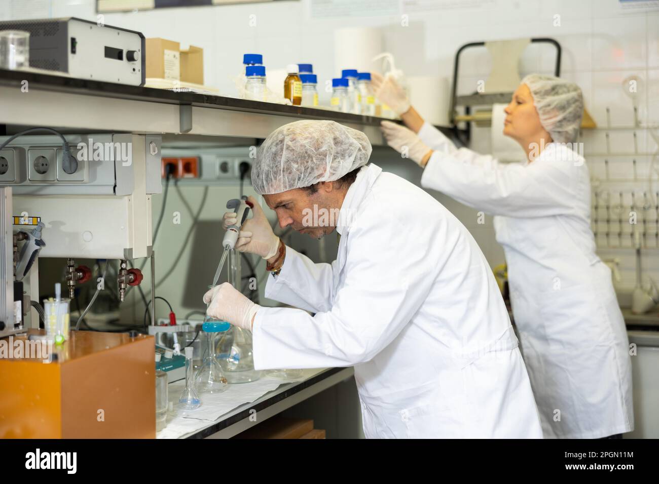 Professional male and female biologists in lab coat examining reaction ...