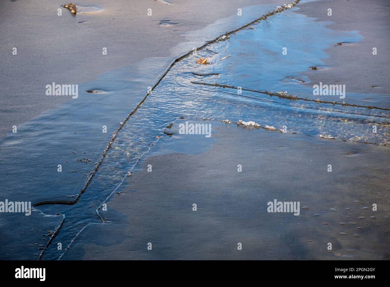Fractures between the melting ice on the surface of a frozen lake in ...