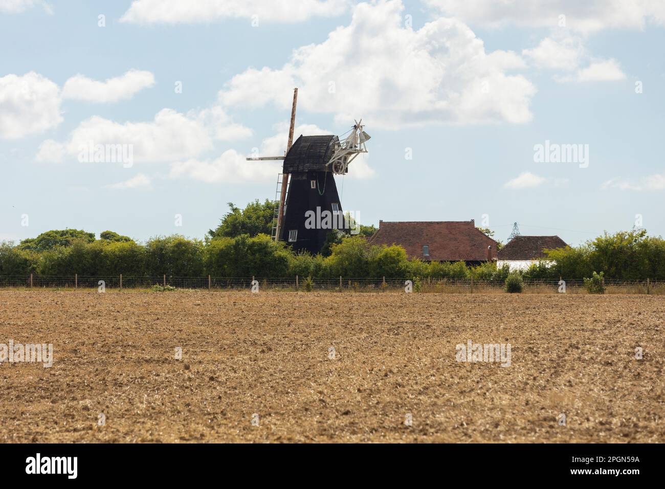 A traditional old English windmill and farm house cottage nestling in ...