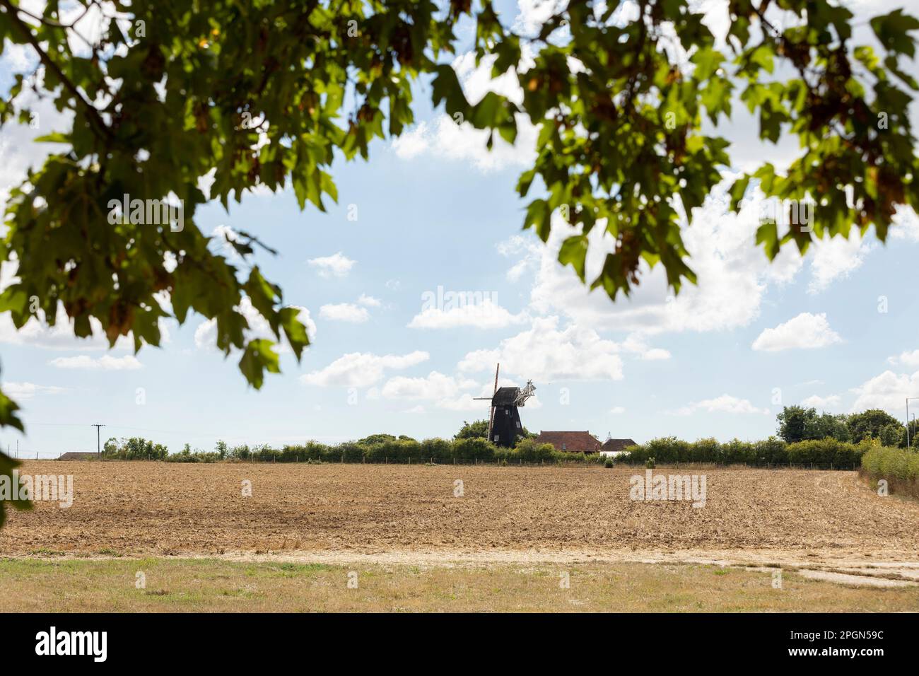 A traditional old English windmill and farm house cottage nestling in ...