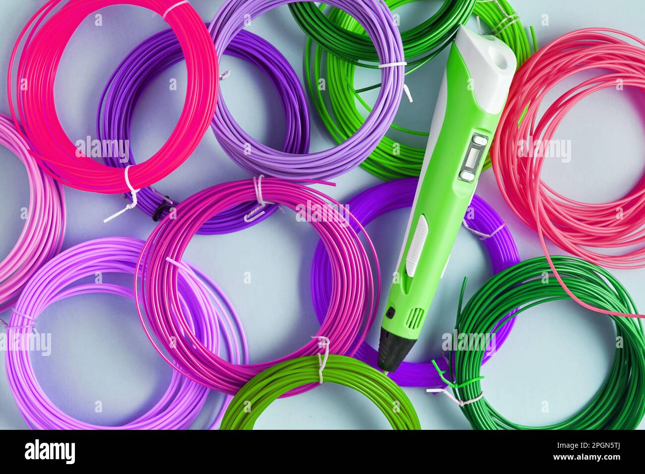 Colorful heap of PLA and ABS plastic skeins with a new 3d pen on top of ...