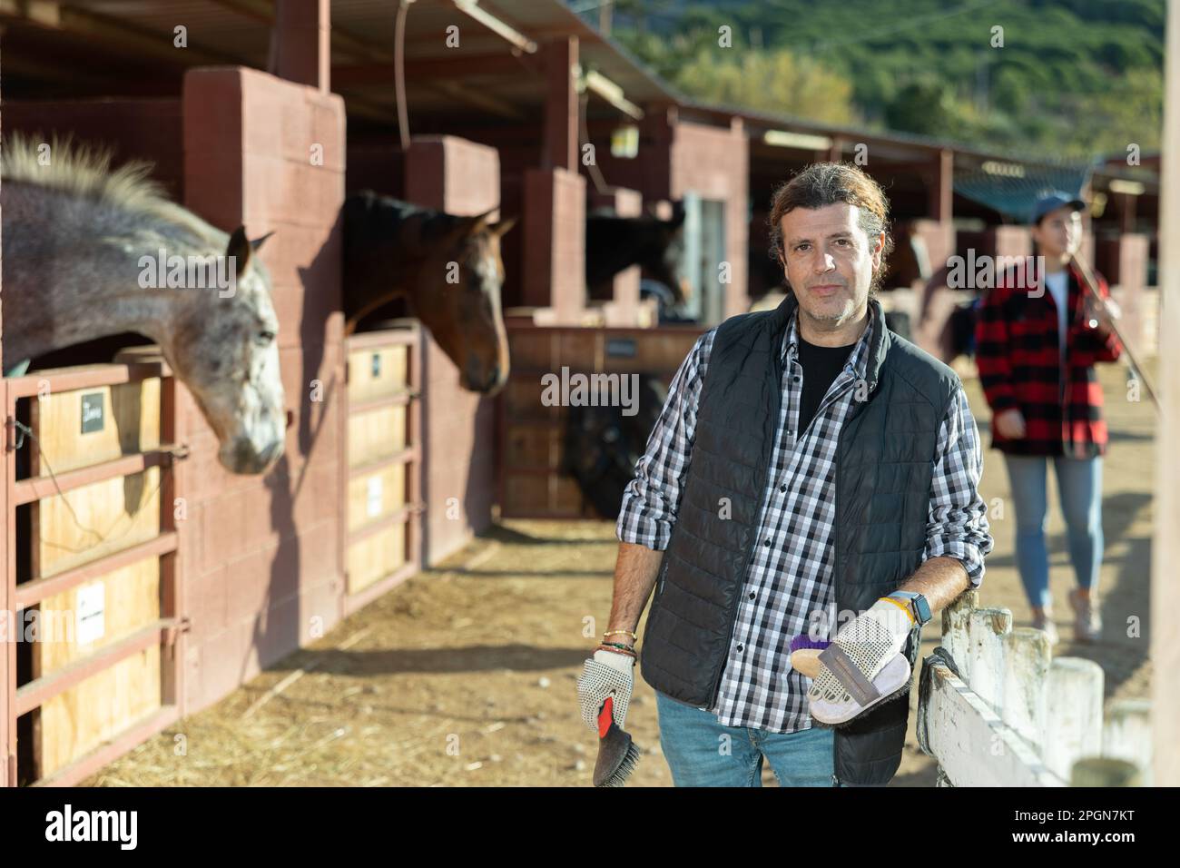 Confident man in front of his farm and stables with horses Stock Photo ...