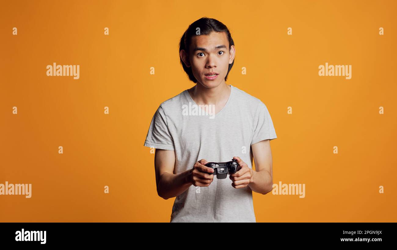 Modern asian man playing videogames on console, using controller or ...