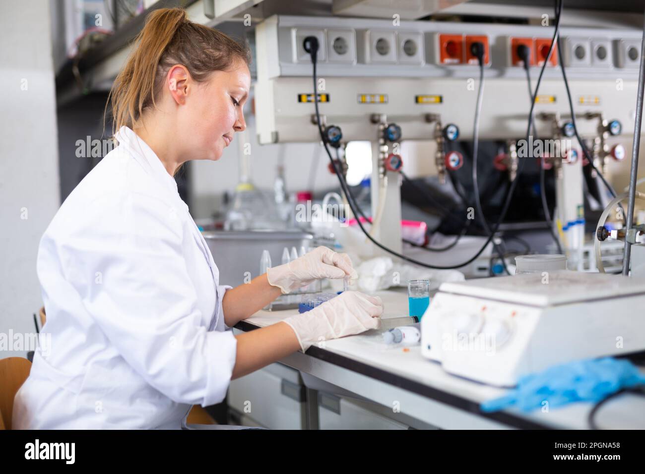 Efficient female lab technician working with reagents in test tubes ...