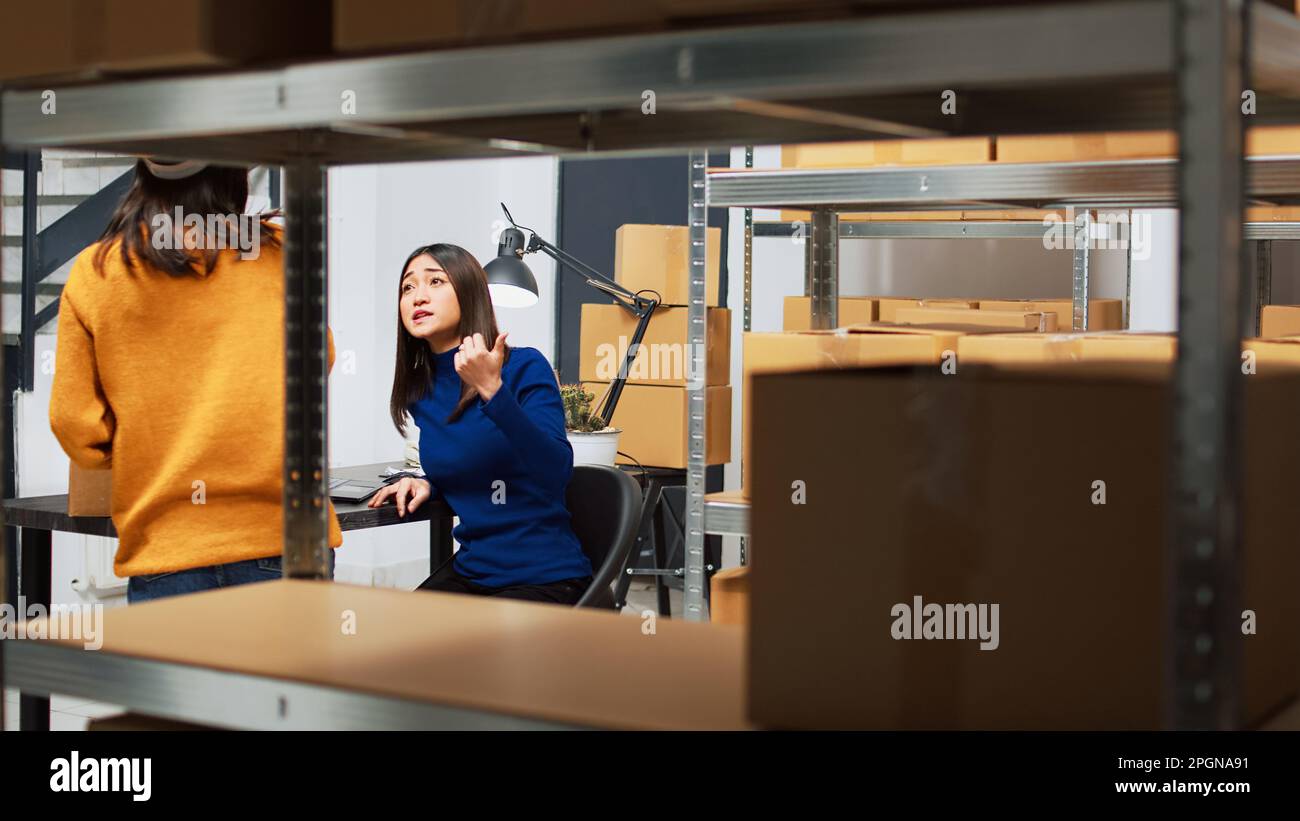 Team of asian workers using laptop to plan shipment, checking quality of goods in warehouse ...