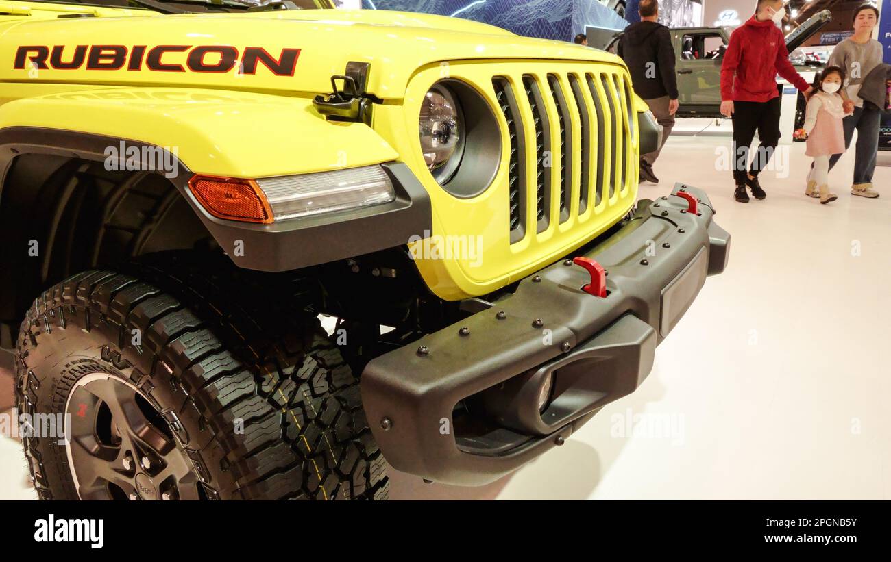 Close up view of yellow Rubicon Jeep car on display. Crowds looking at ...