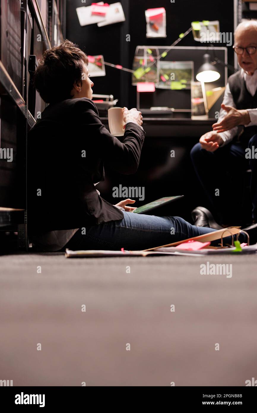 Tired police officer analyzing victim report in arhive room, discussing ...