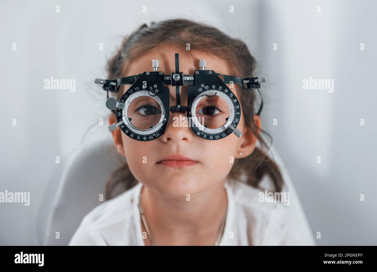 Cute little girl is in ophthalmology clinic with special tool on eyes ...