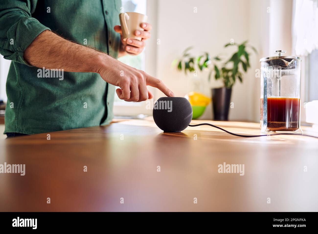 Man standing at home holding coffee cup switching on loudspeaker Stock ...
