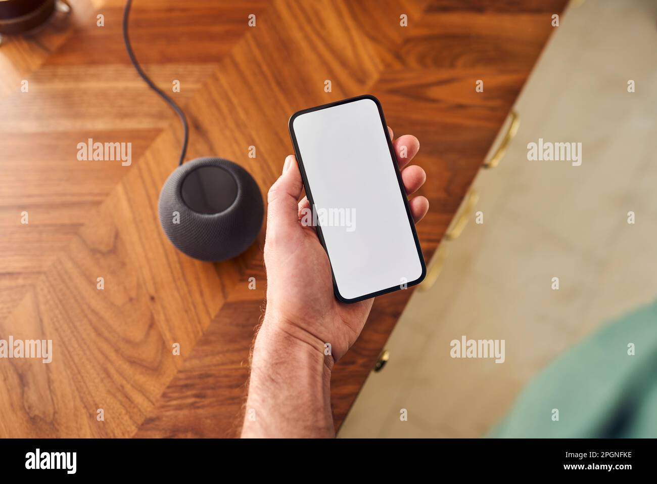 Man connecting phone with blank screen to smart speaker on kitchen ...