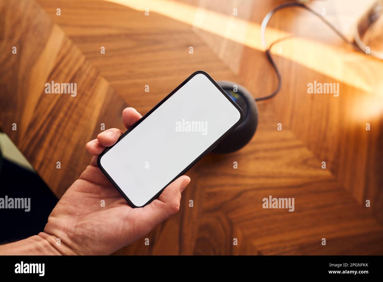 Man connecting phone with blank screen to smart speaker on kitchen ...