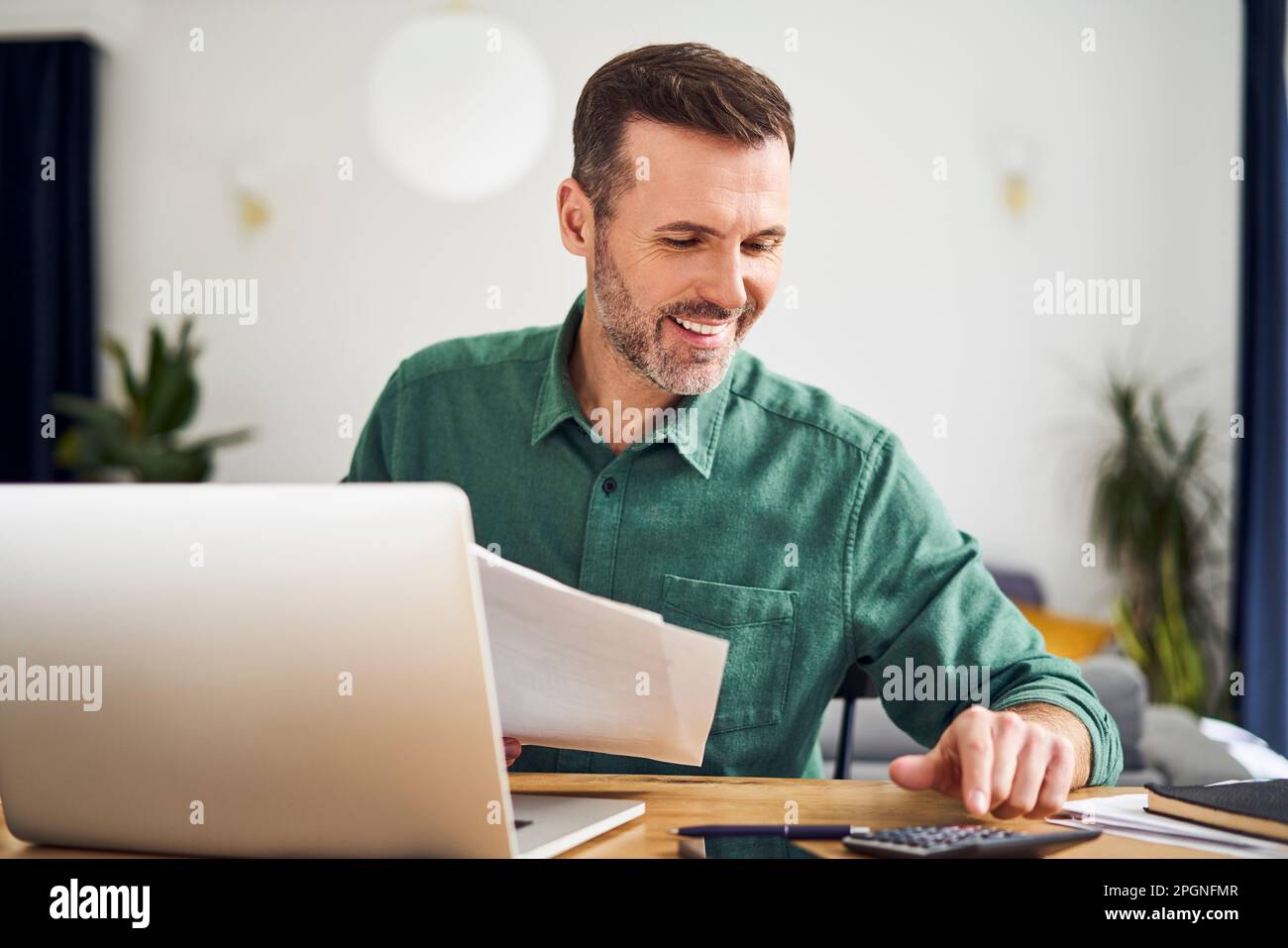 Contented man doing paperwork calculating finaces Stock Photo - Alamy