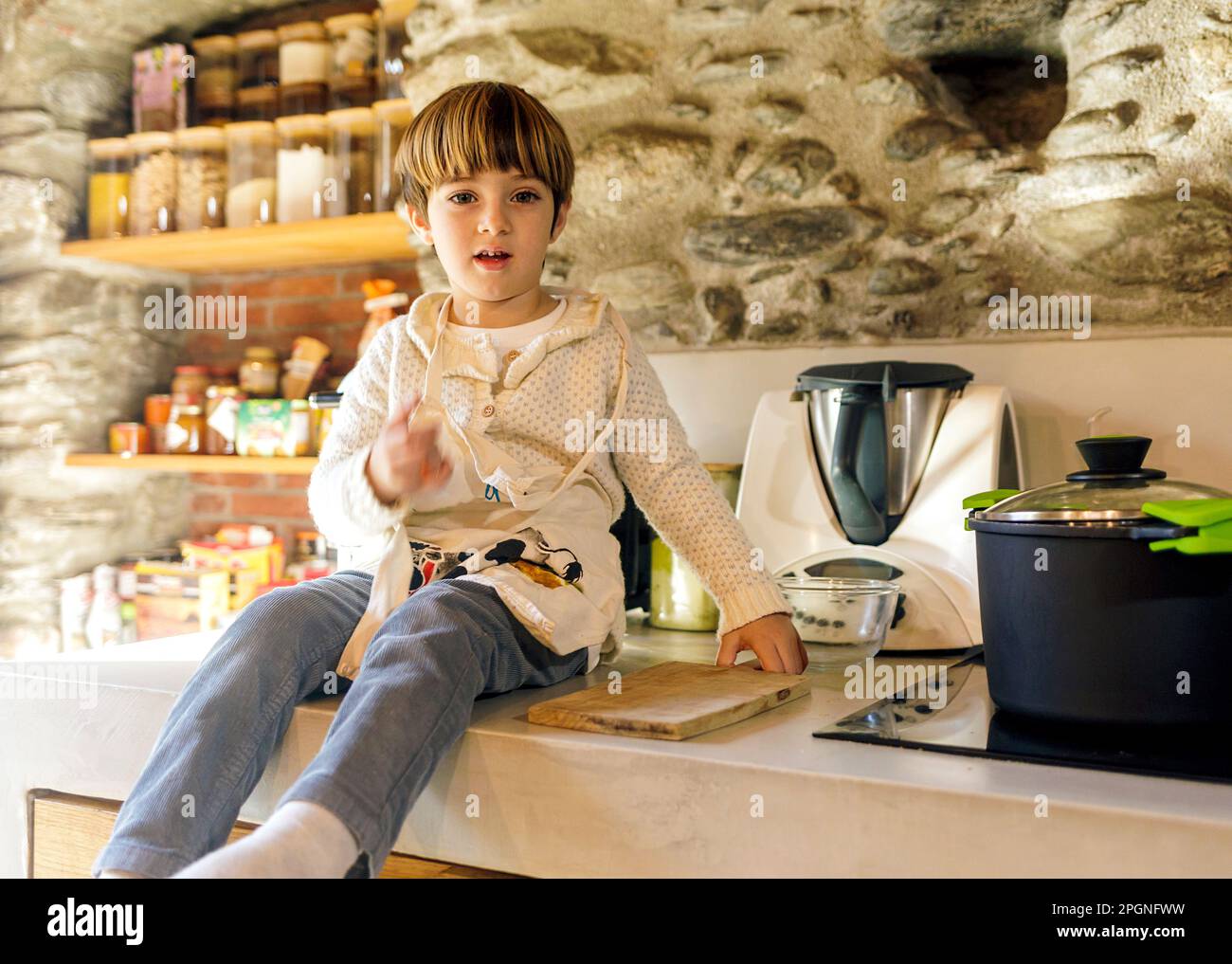 Cute boy sitting on kitchen counter at home Stock Photo - Alamy