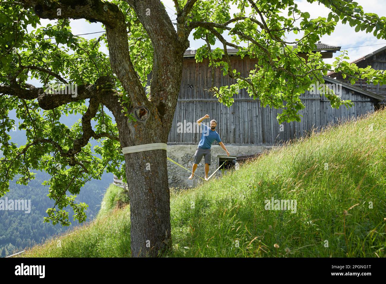 Man balancing on tightrope at hill Stock Photo - Alamy