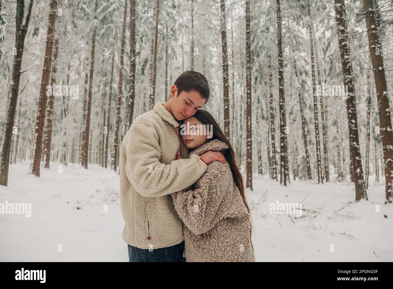 Teenage boyfriend hugging girlfriend in snowy forest Stock Photo - Alamy