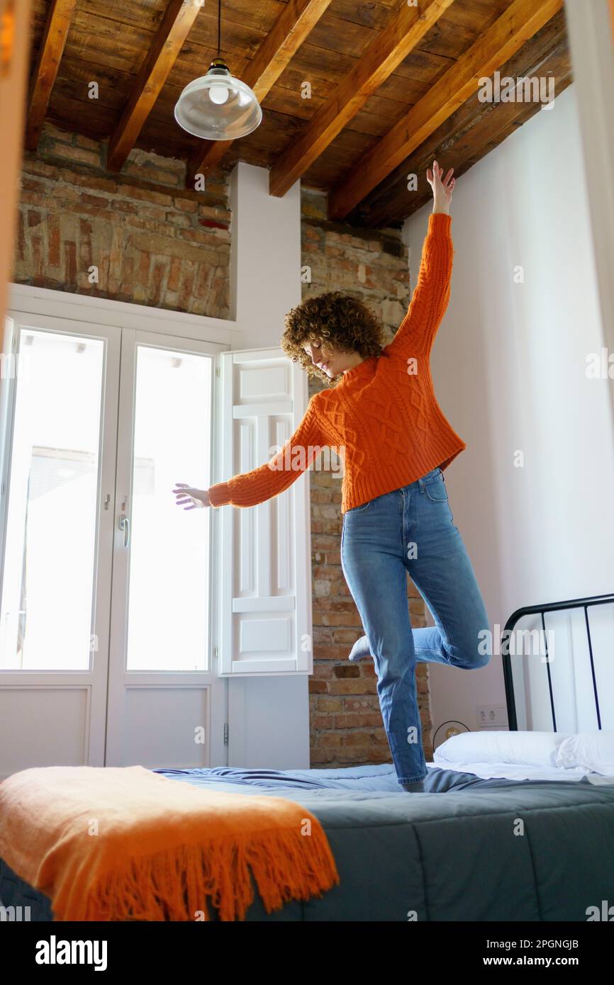 Happy woman dancing on bed in bedroom at home Stock Photo - Alamy